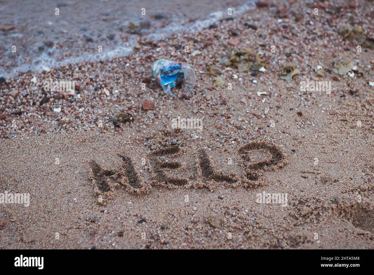 Help message written on the beach next to plastic waste Stock Photo - Alamy