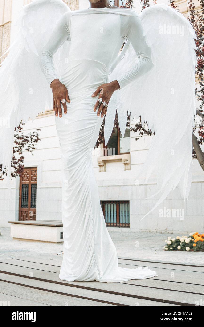 Shot of cut face model wearing white dress with angel wings and posing ...