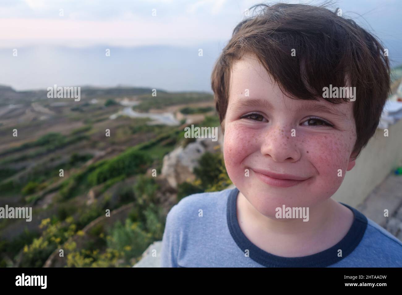 Closeup portrait of a Caucasian boy smiling on the camera with a blurry ...
