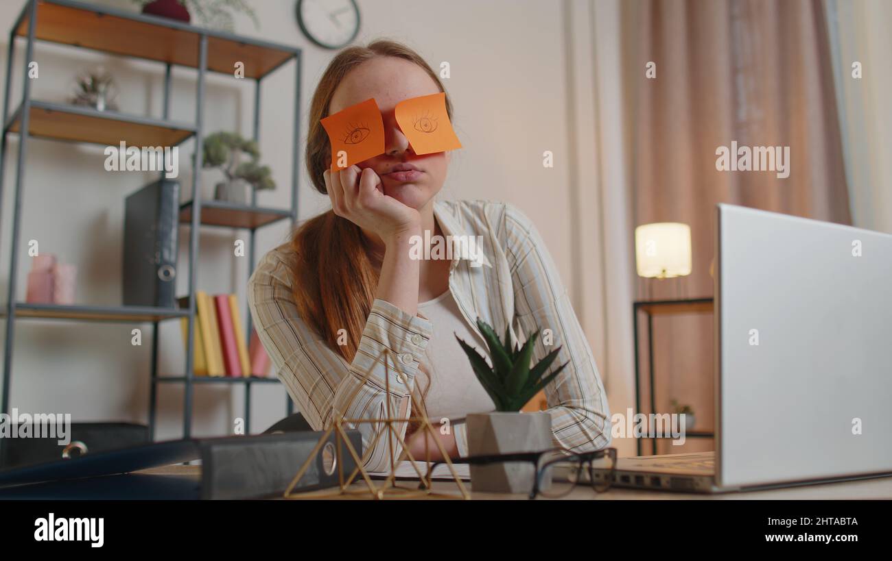 Tired woman teacher using laptop computer with funny stickers on eyes ...