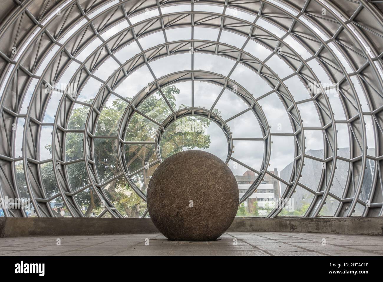 Ancient stone sphere enclosed by a modern sphere in front of the ...