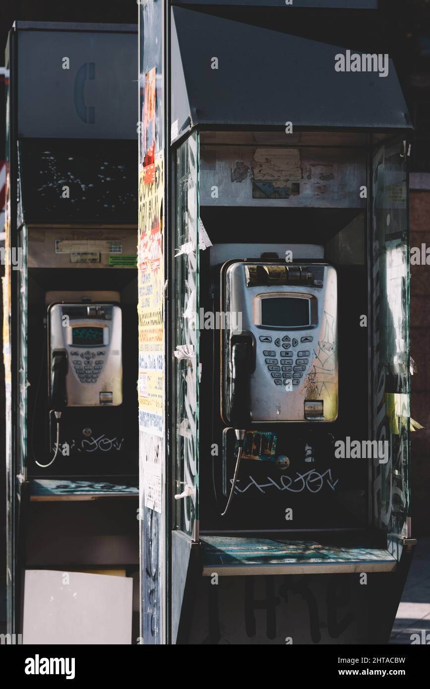 Old public phones in boxes covered in old weathered posters in Madrid ...