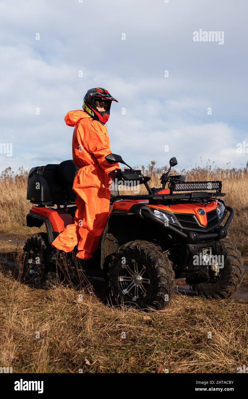 Young athletic woman driving an orange Quadro bike in nature wearing a ...