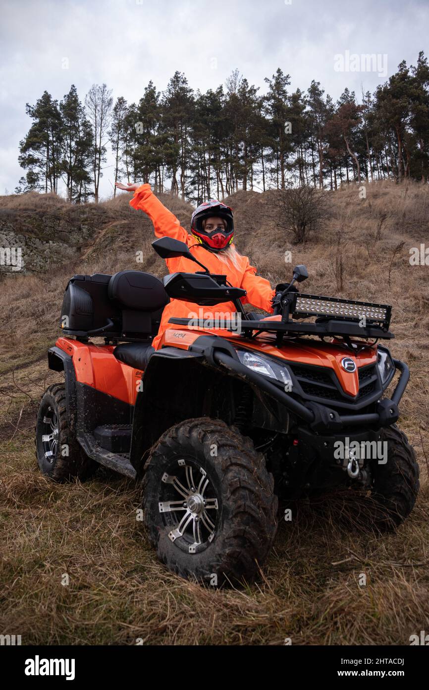 Young athletic woman driving an orange Quadro bike in nature wearing a ...