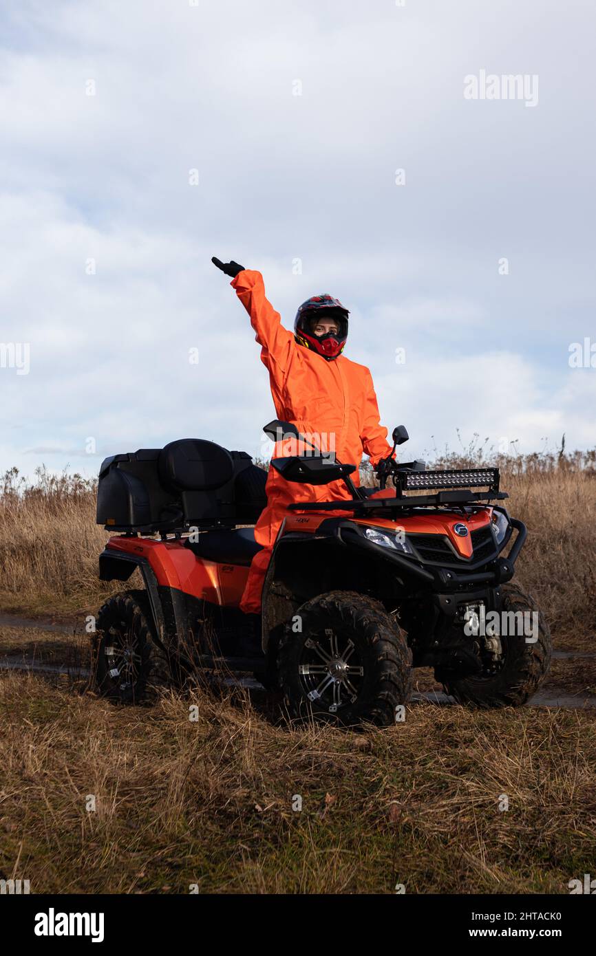 Young athletic woman driving an orange Quadro bike in nature wearing a ...