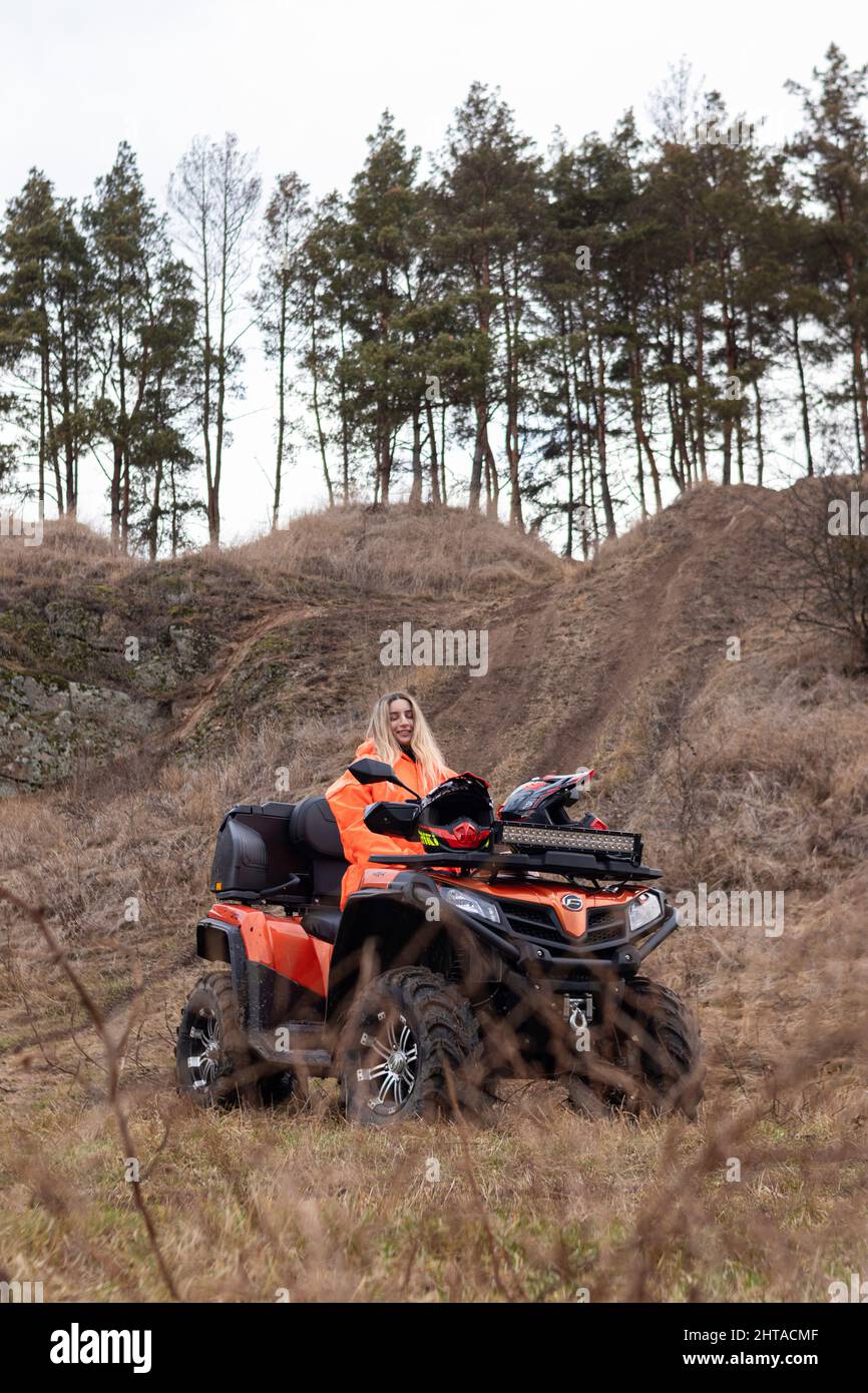 Young athletic woman driving an orange Quadro bike in nature wearing a ...