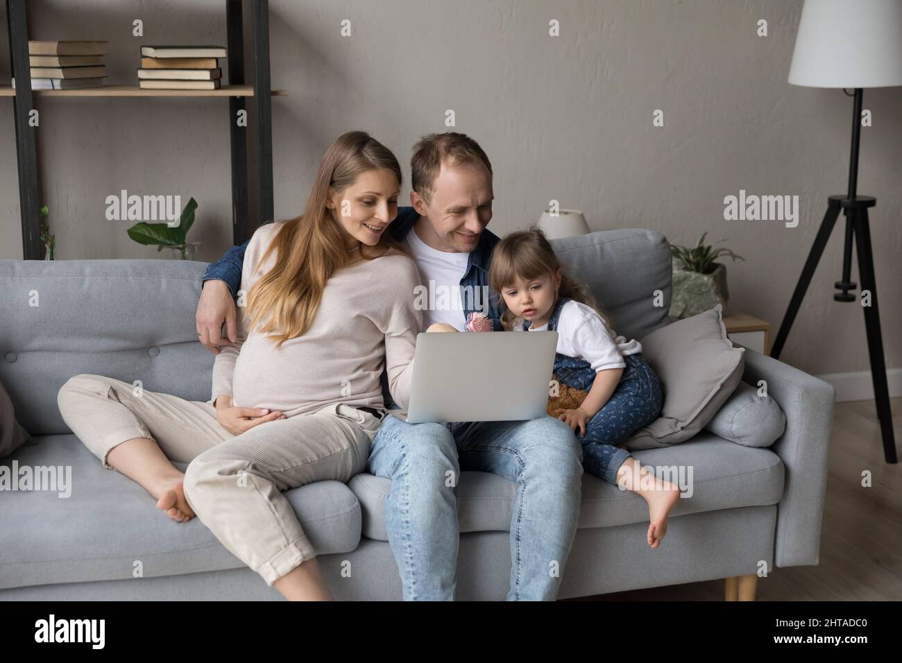 Happy expecting parents and little daughter kid relaxing on couch Stock ...