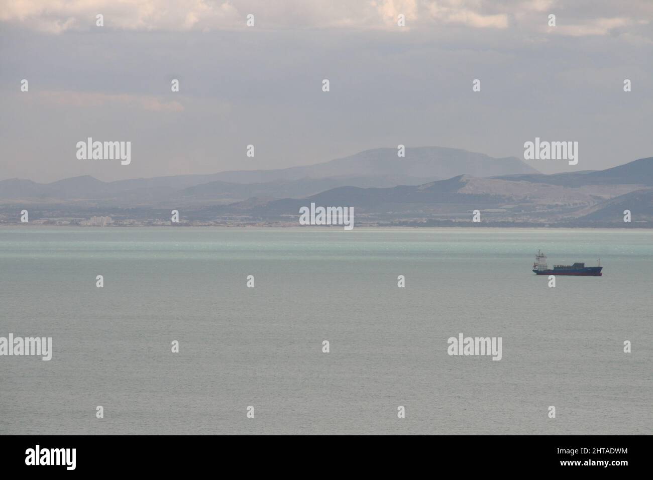 Beautiful landscape of a sea with a single ship sailing and mountains ...