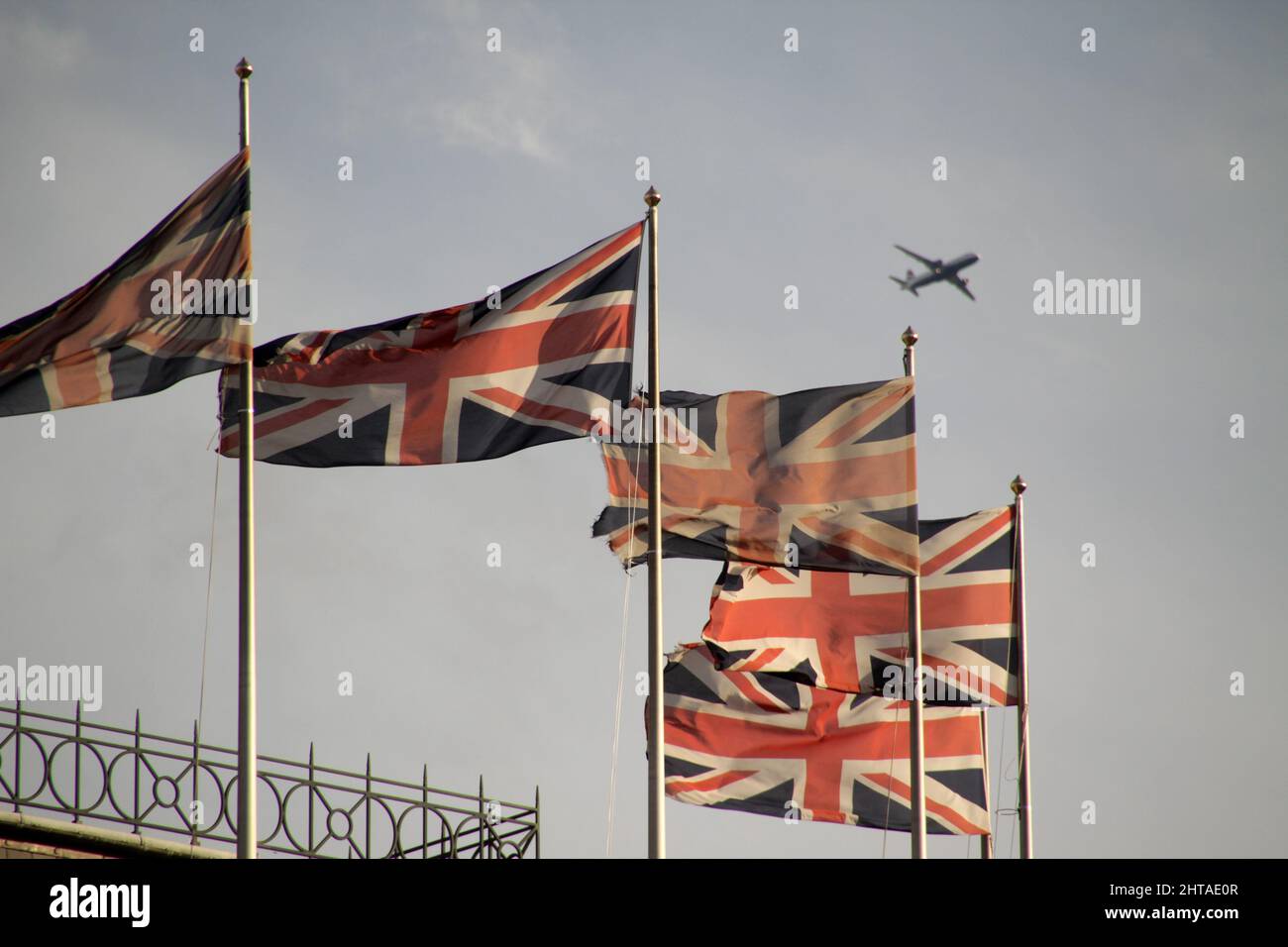Airplane flying in the sky behind British flags Stock Photo - Alamy