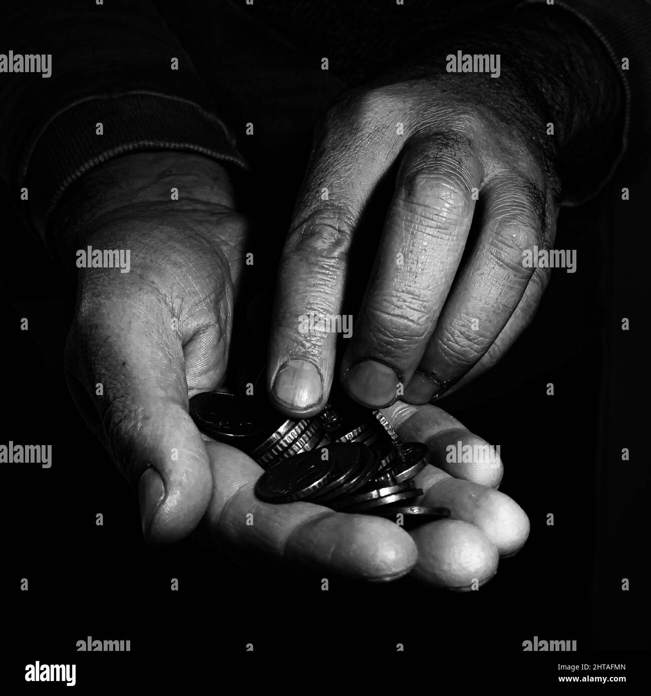 Grayscale closeup of male hands holding and counting coins with dark ...