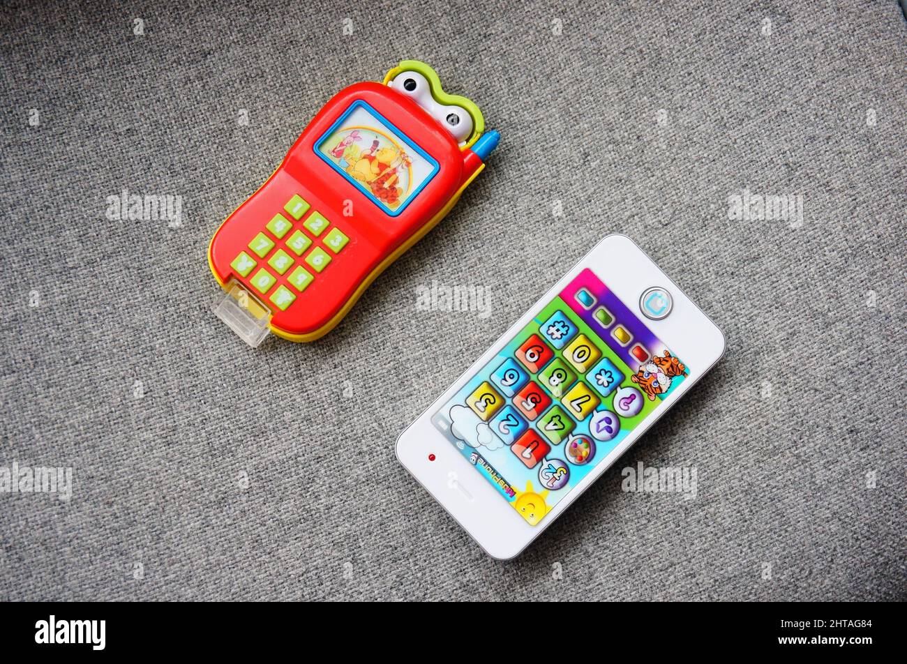 Closeup shot of the two plastic toy phones laying on the gray sofa ...