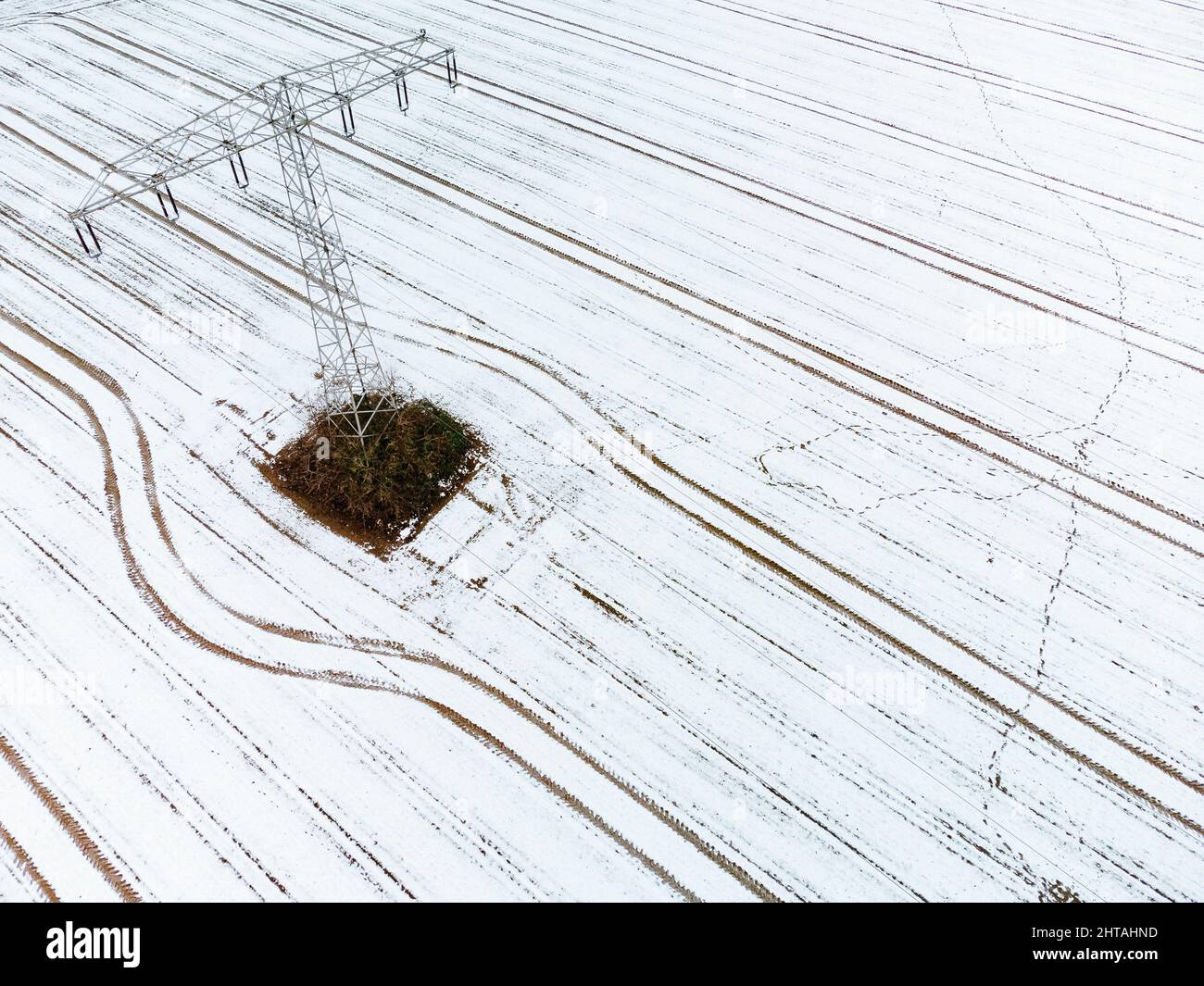 Aerial view of a snowy agricultural field with a transmission tower ...