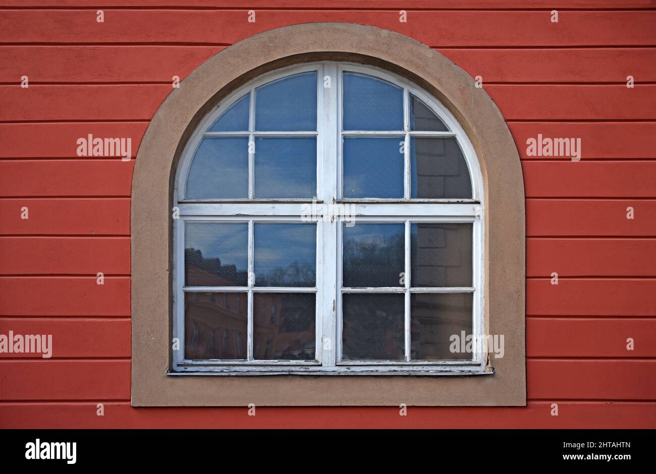Exterior of the red-colored house wall with old wooden arched window ...
