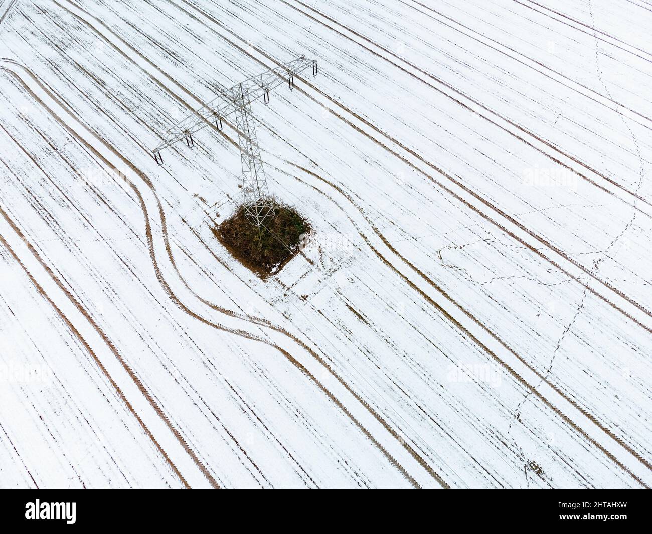 Aerial view of a snowy agricultural field with a transmission tower ...