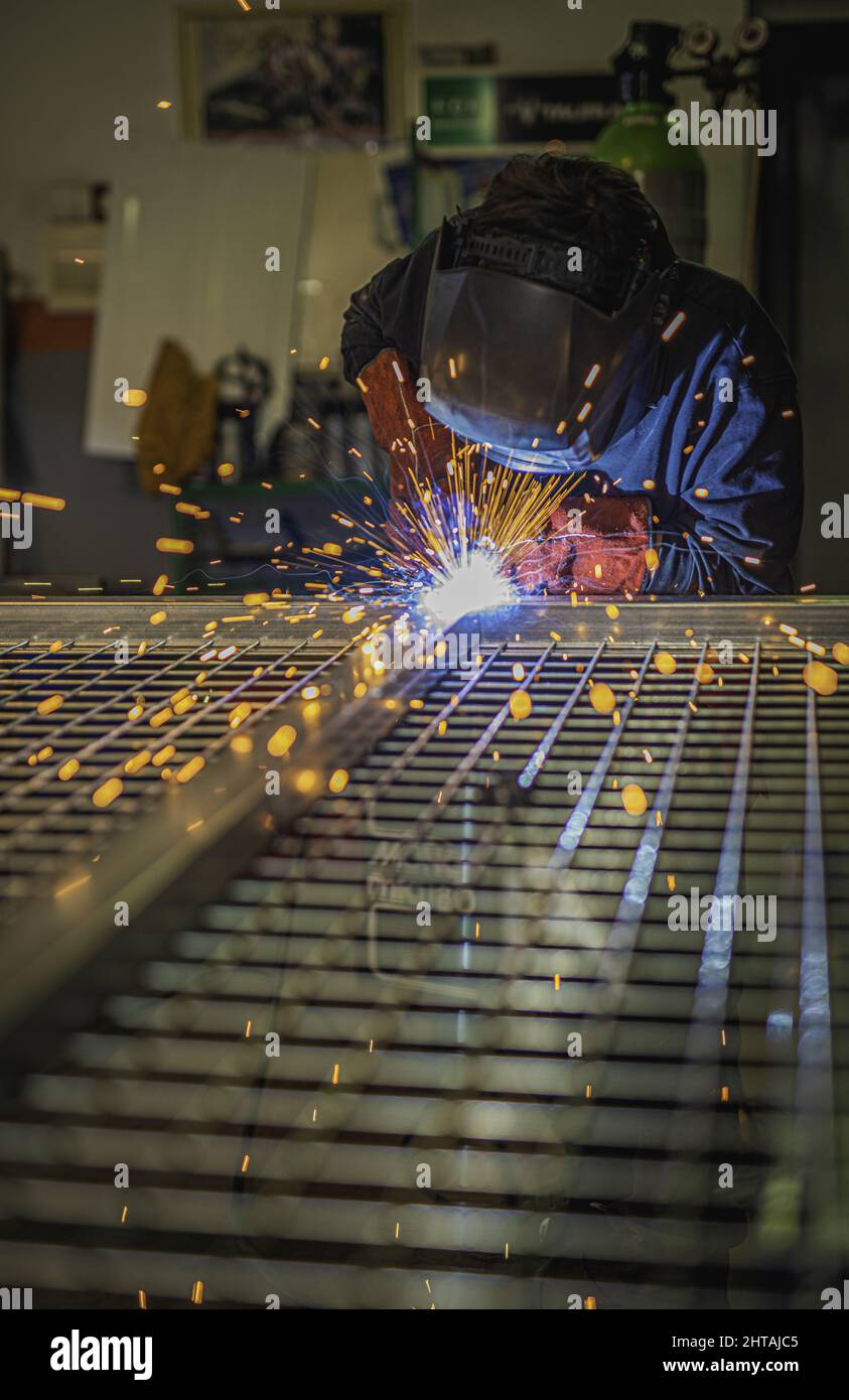 Professional welder with face protection mask welding a door in the ...