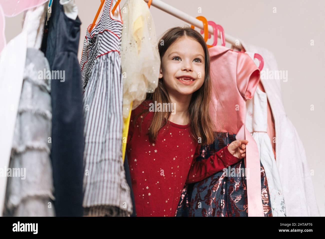 Smiling little girl with long dark hair in red dress among her ...