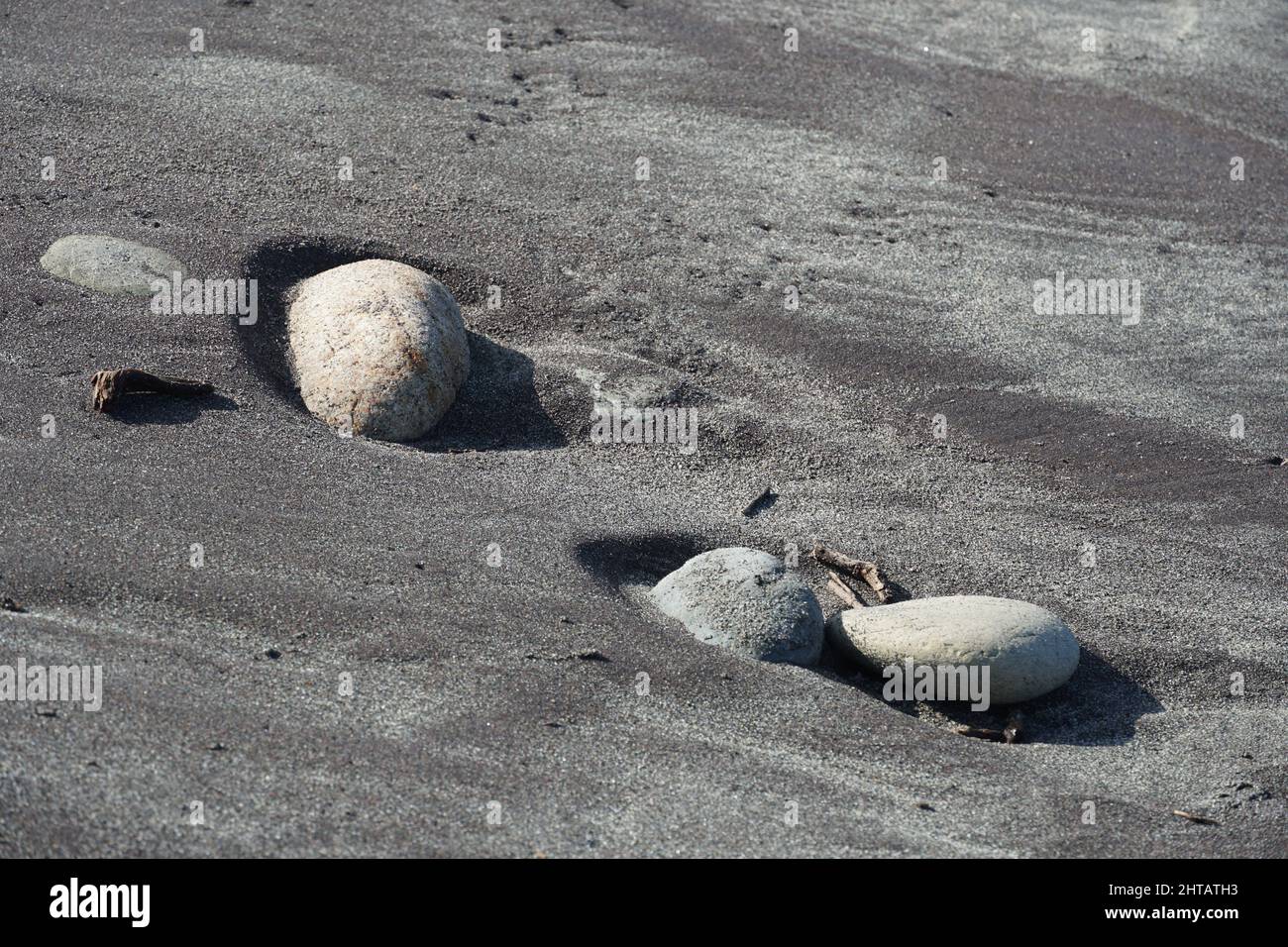 Close-up shot of big stones on the sand in Awatuna beach in the daytime ...