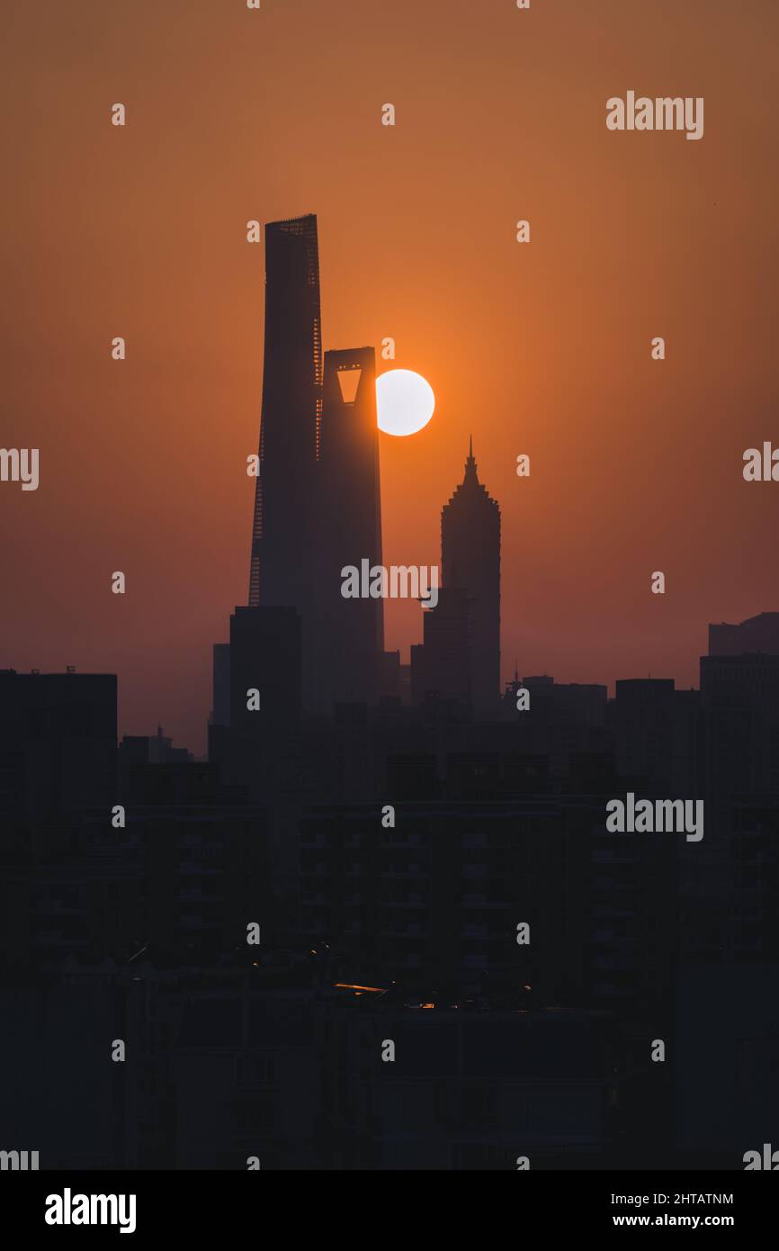 Vertical shot of an orange sun setting near modern buildings Stock ...