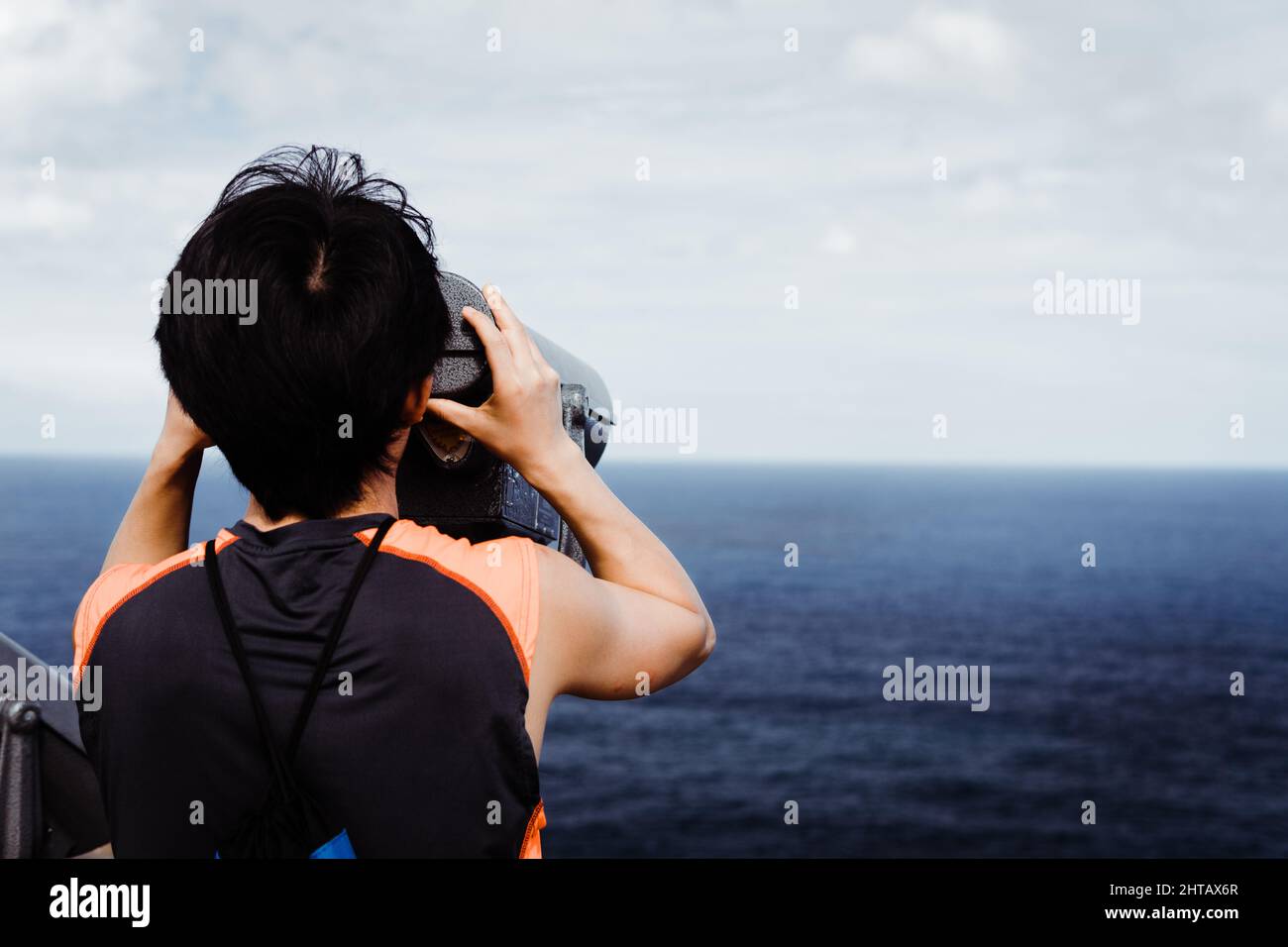 Back view of a man using a telescope to look out over the ocean Stock ...