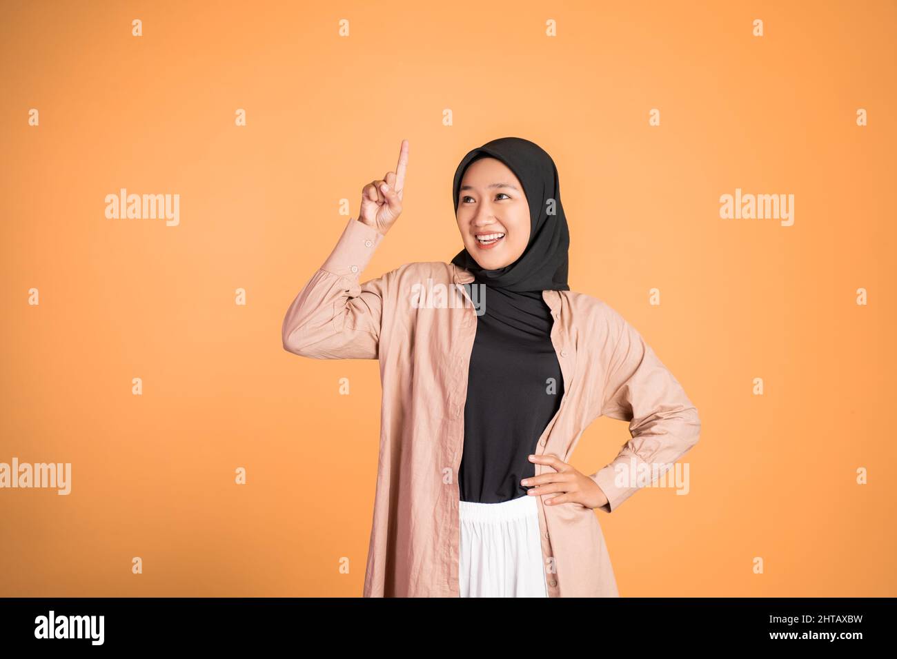 Smiling hijab woman with finger pointing up hand gesture Stock Photo ...