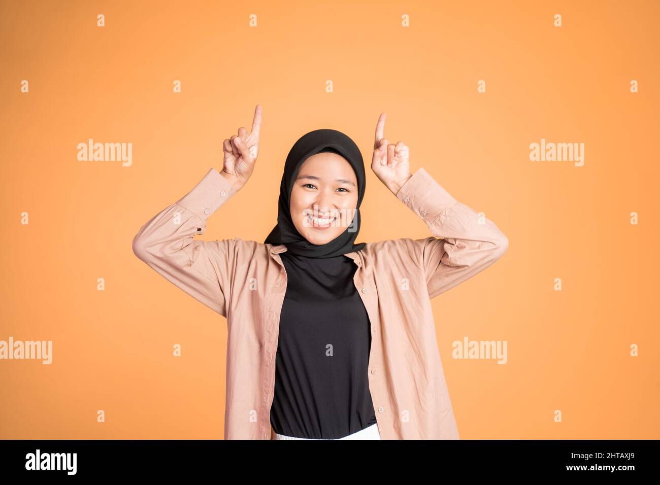 Smiling hijab woman with finger pointing up hand gesture Stock Photo ...