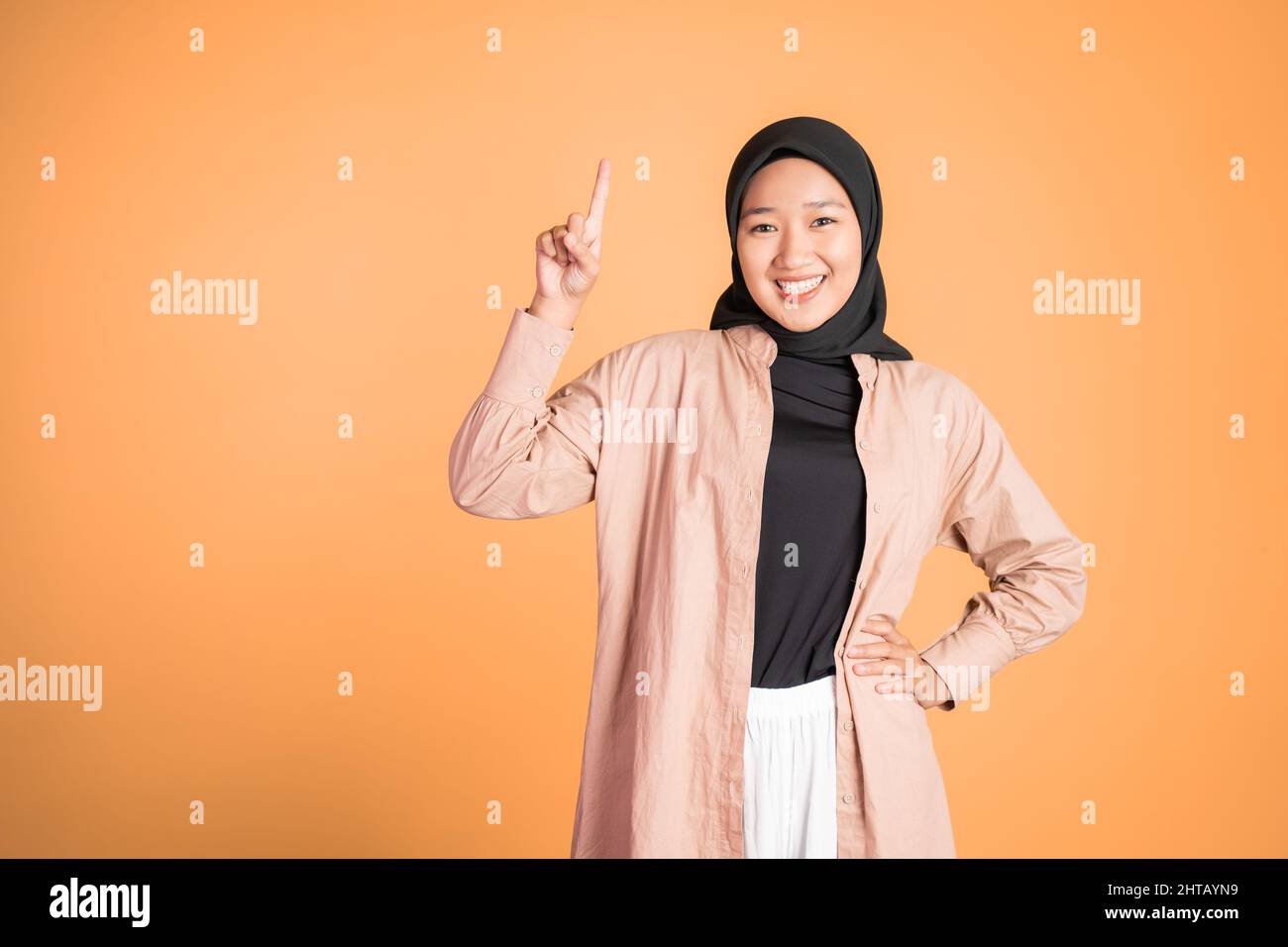Smiling hijab woman with finger pointing up hand gesture Stock Photo ...