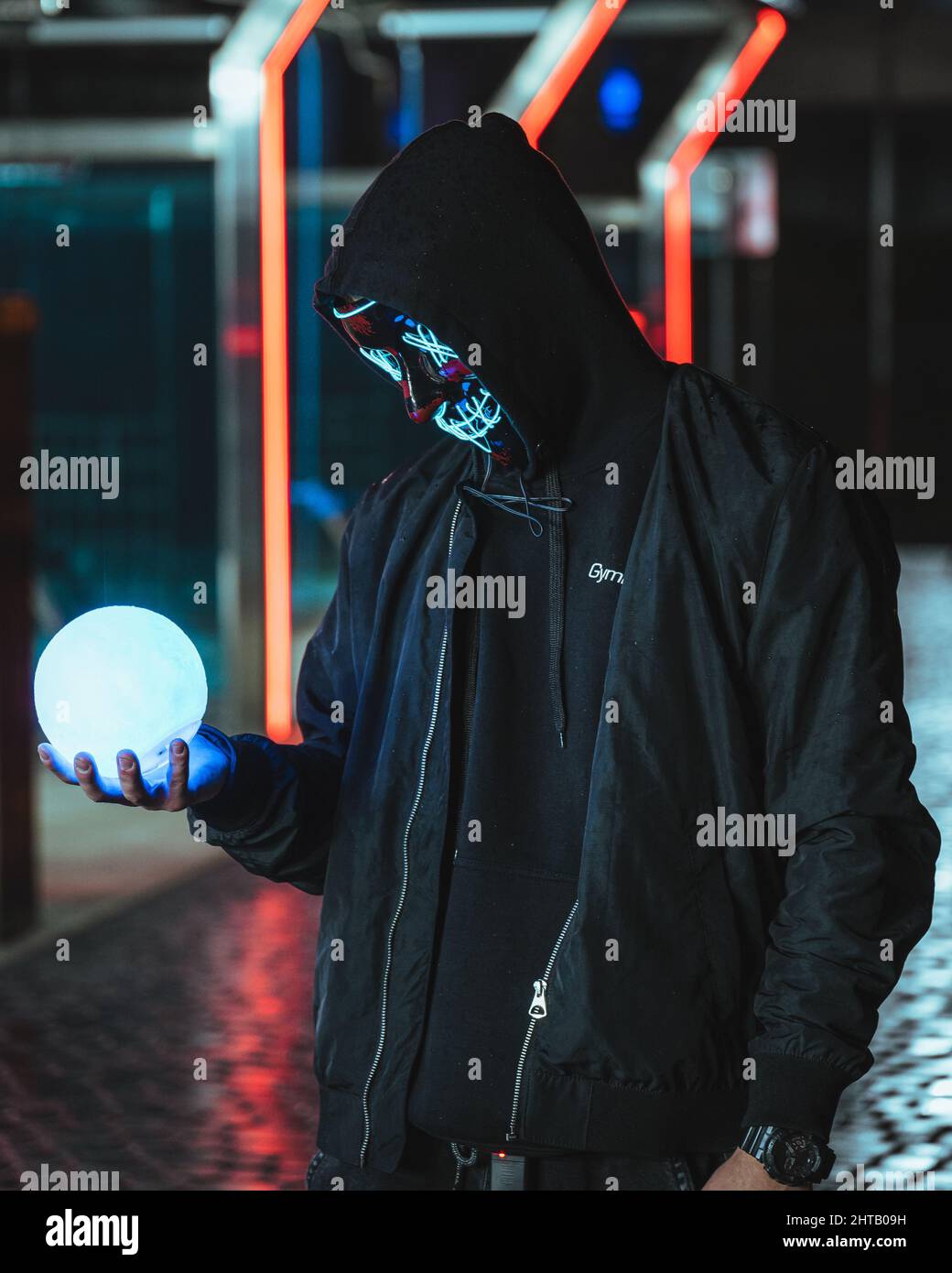 Man in a blue neon mask holding the moon as a magician Stock Photo - Alamy