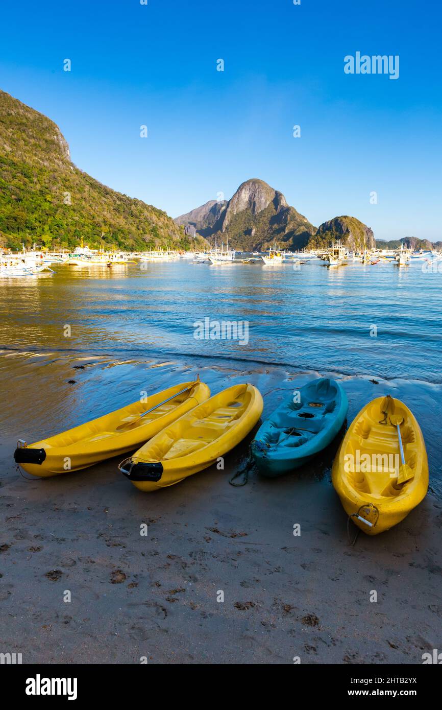 Vertical shot of one blue and three yellow kayaks at the beach in El ...
