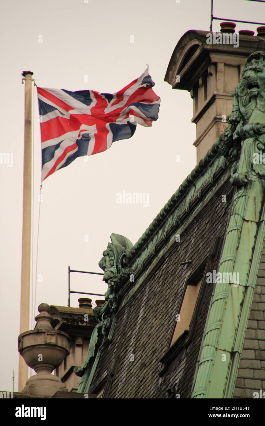 A vertical shot of the flag of UK near a modern building in London ...
