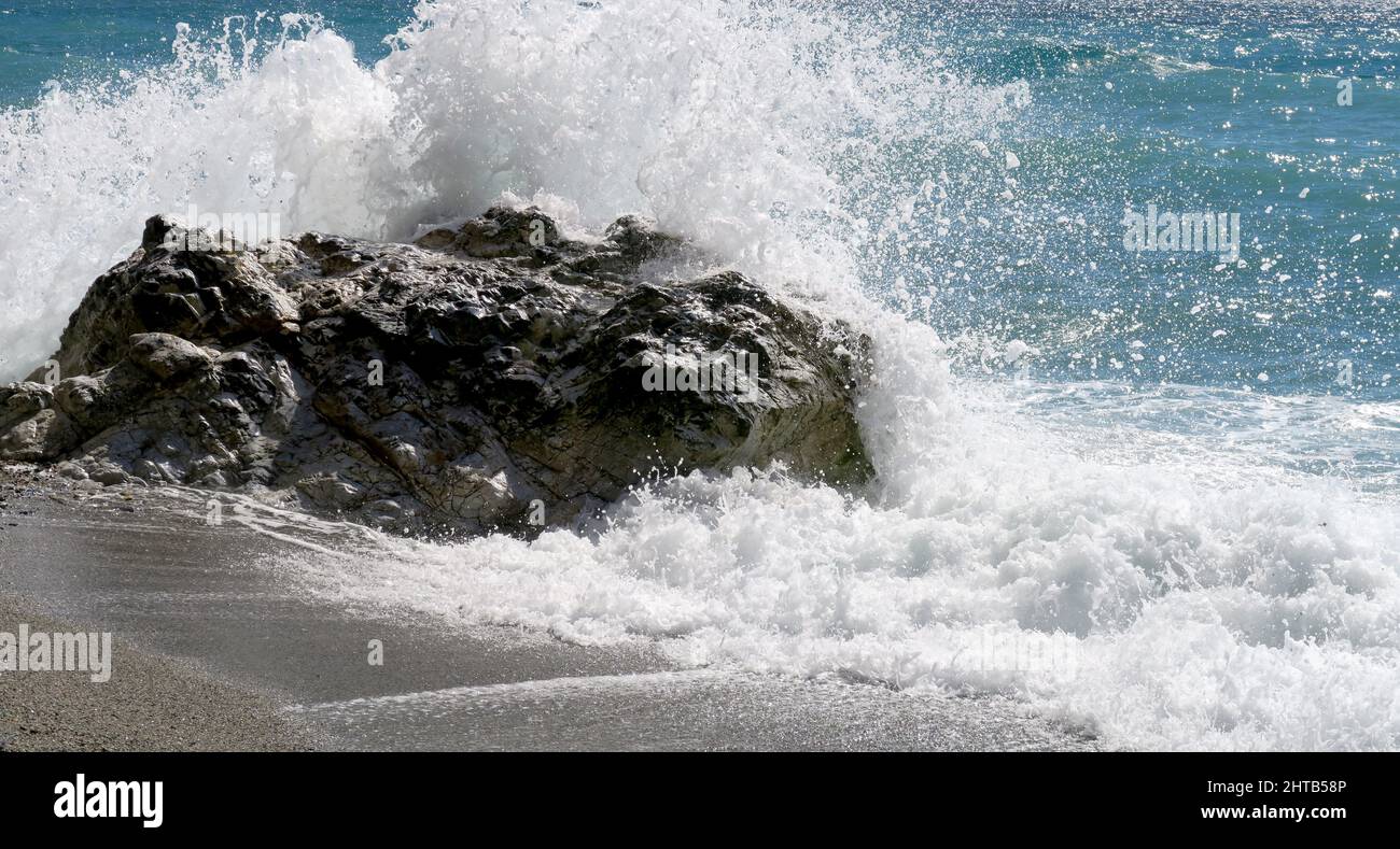 Wave hitting a rock on the beach Stock Photo - Alamy