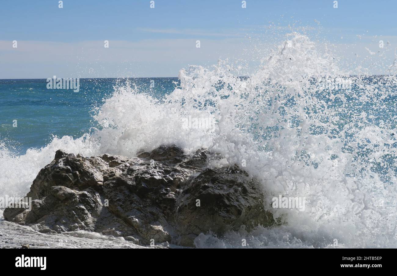 Wave hitting a rock at the cost Stock Photo - Alamy