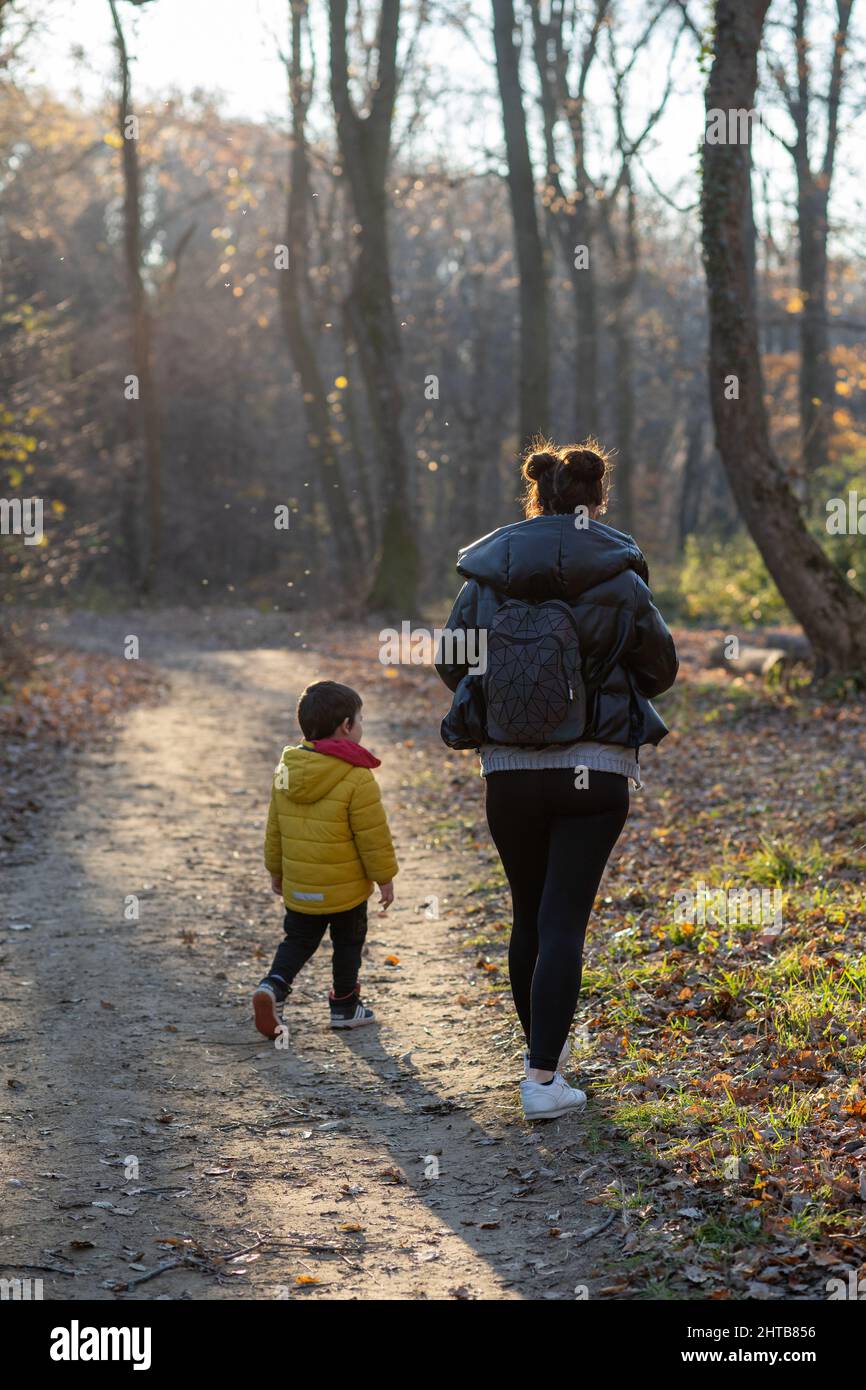 Vertical back view of a baby and his mother walking along the path in ...