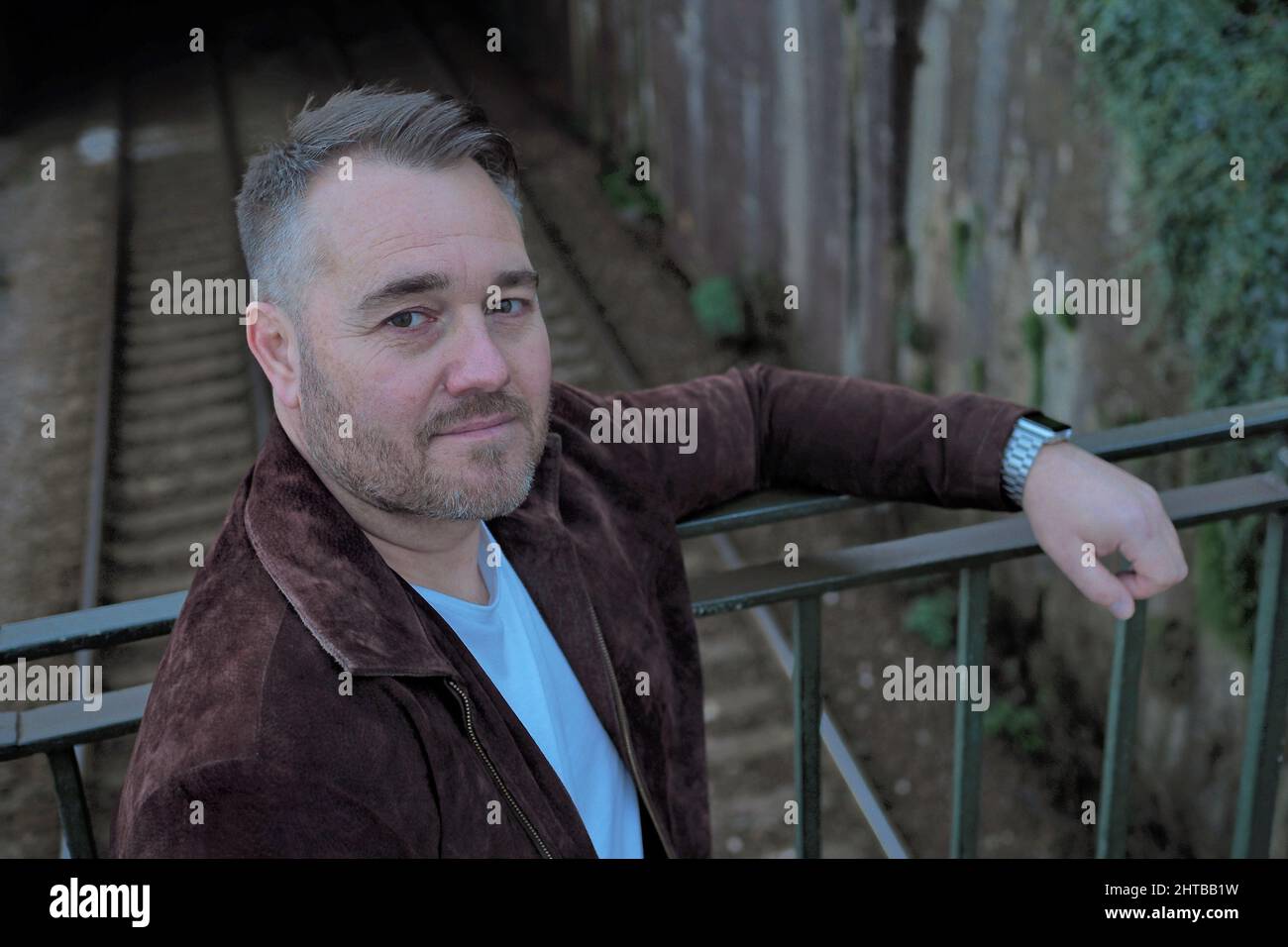 Bearded handsome middle aged Caucasian male leaning against the metal ...