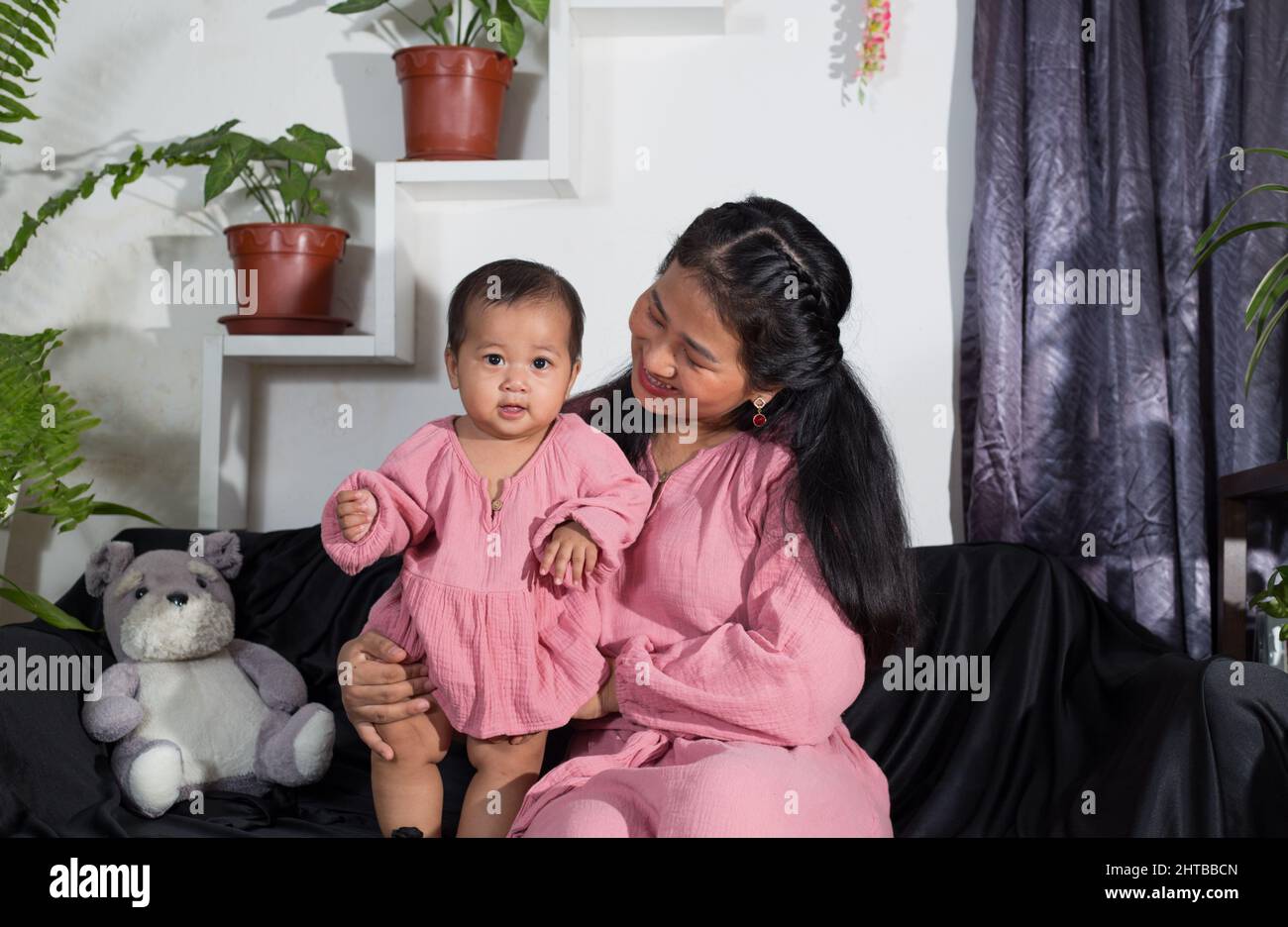 Young, cheerful Southeast Asian mother sitting and posing with her ...