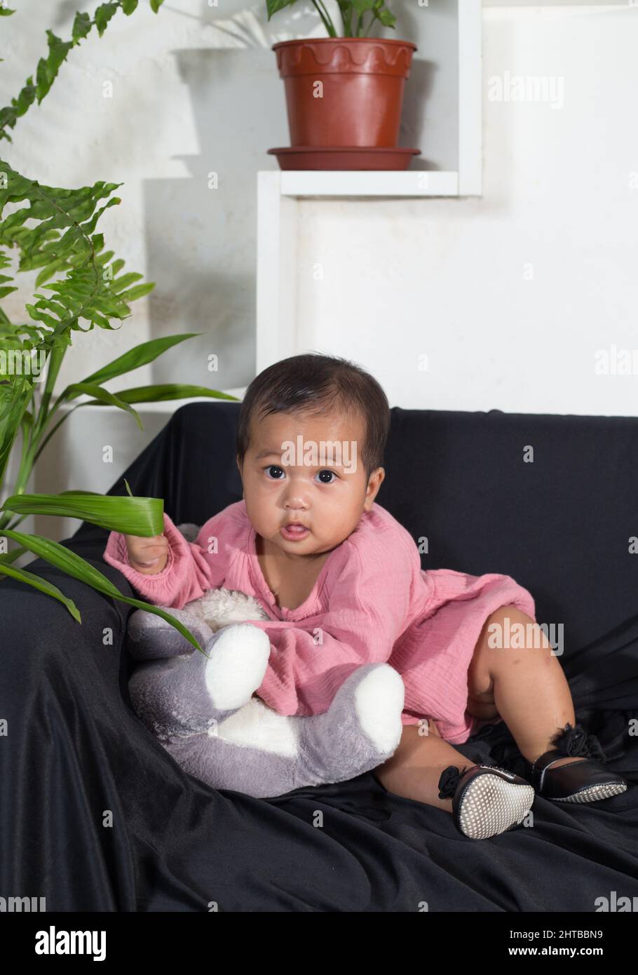 Adorable little child in a pink dress sitting on the sofa Stock Photo ...