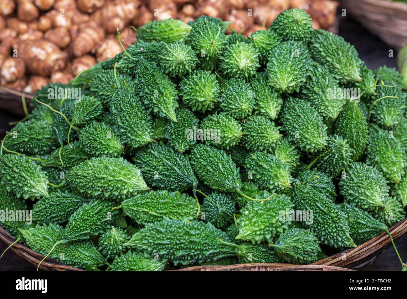 Small green bitter gourds are kept in baskets for sale in the market ...