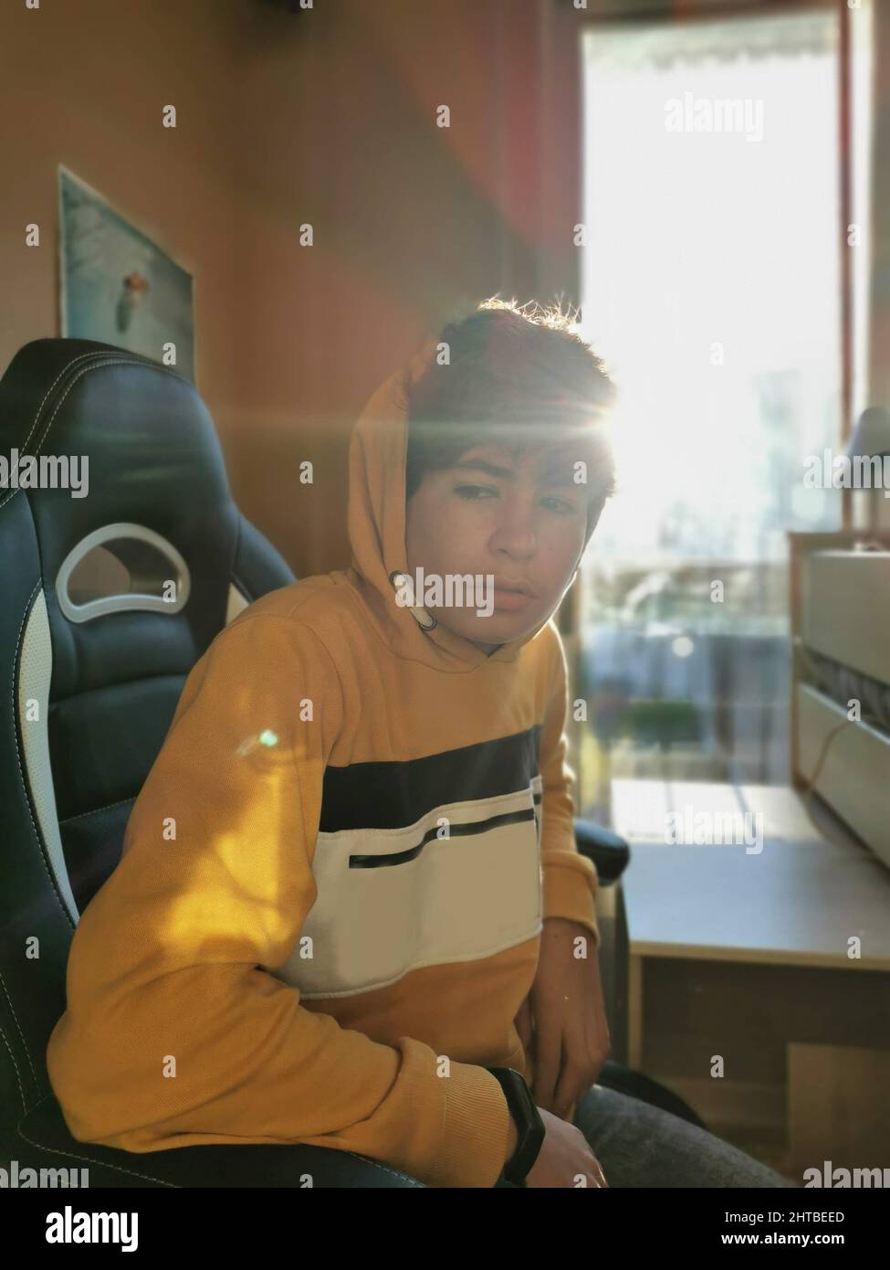 Hispanic guy with a yellow hoodie sitting in the living room with ...