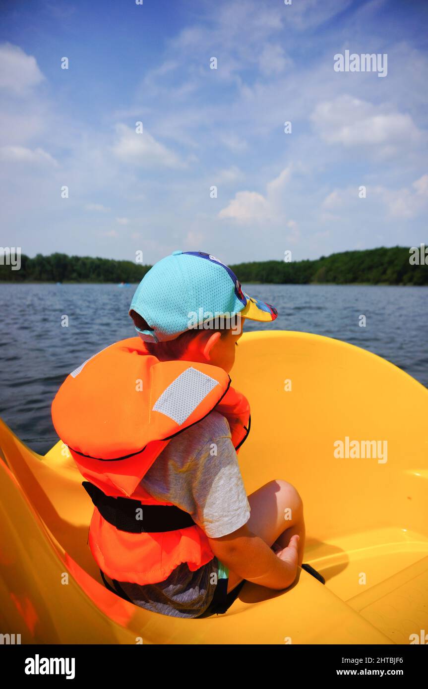 Vertical shot of a young boy sitting in a pedal boat on the Kierskie ... Vertical shot of a young boy sitting in a pedal boat on the Kierskie ...