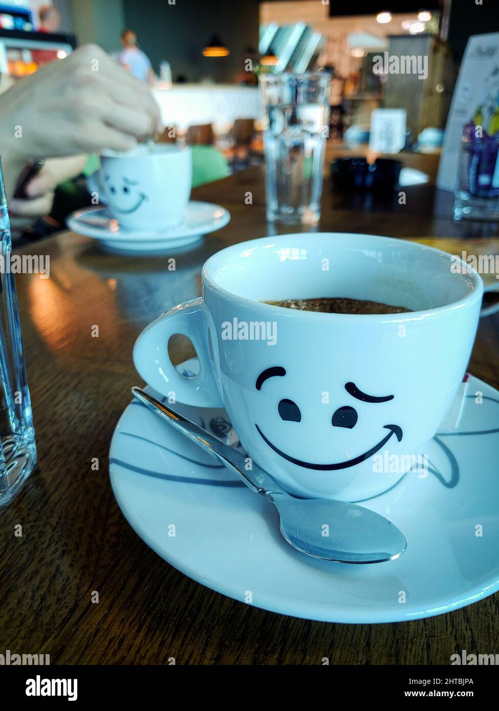 Vertical closeup of a blue cup of coffee with a smiling happy face ...