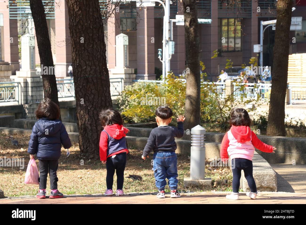 Rear view of four little children walking in the same direction in the ...