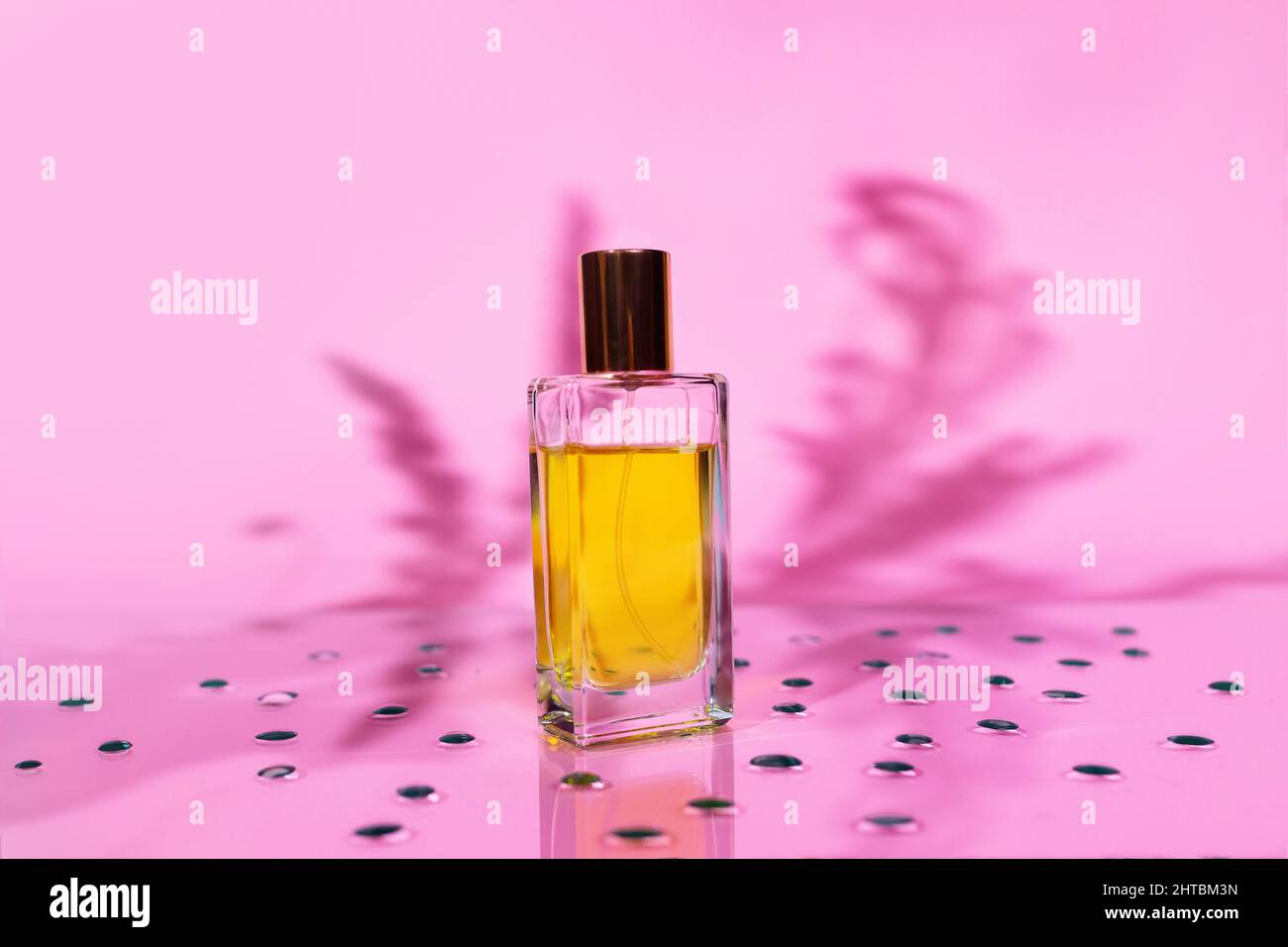Transparent rectangular bottle of golden perfume on pink background ...