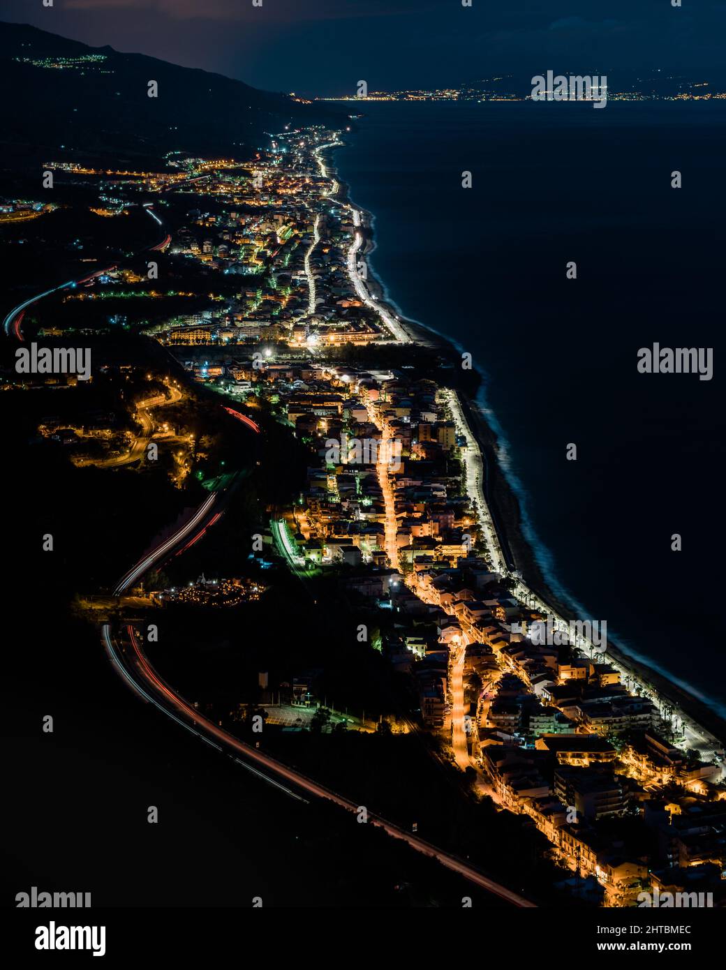 Aerial view of buildings with a Mediterranean sea at night in Sicily ...