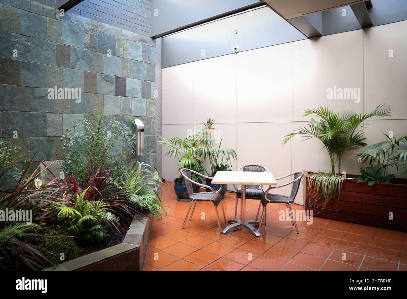 Resting zone with a table, chairs and green plants Stock Photo - Alamy