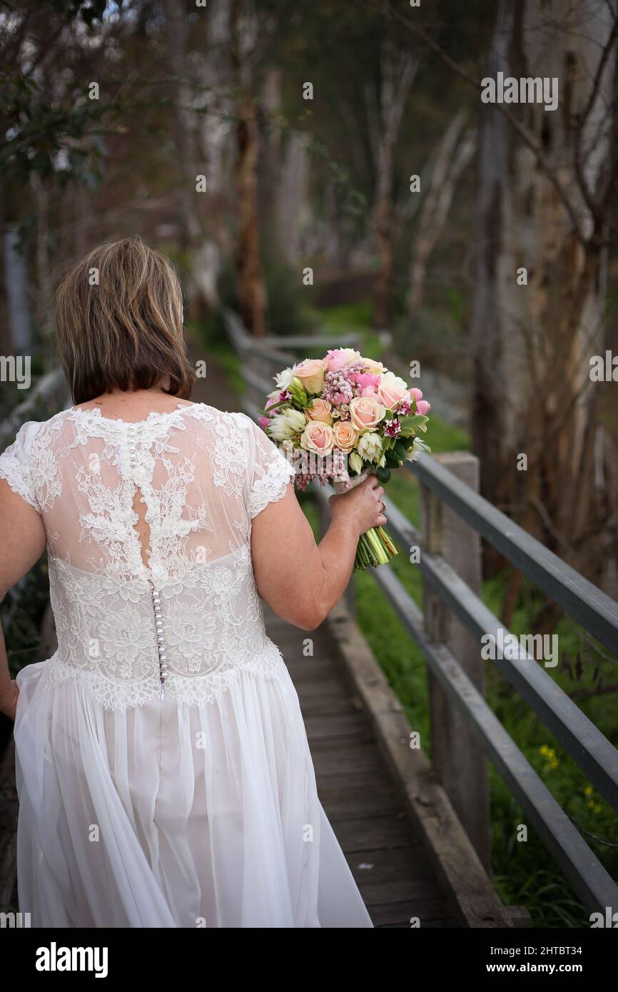 Vertical shot of a bride holding a beautiful bouquet walking on a ...