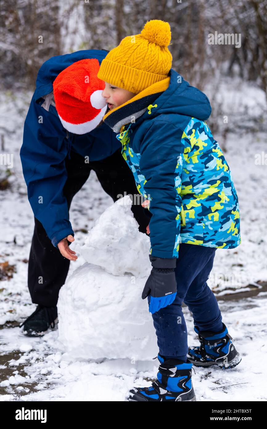 Man and a young boy making a snowman at the Rusalka park on a cold ...