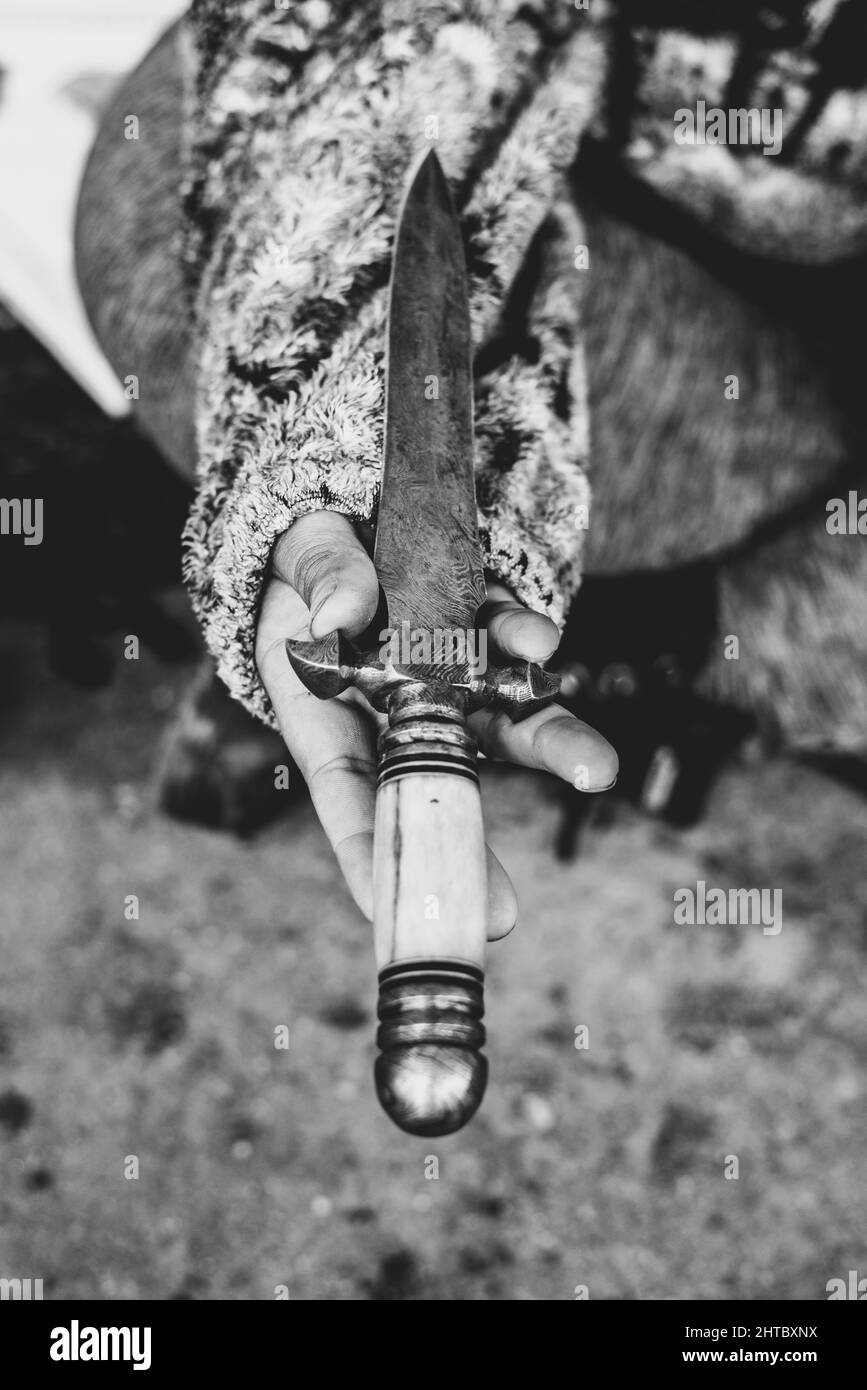 Vertical grayscale shot of a person passing you an old dagger Stock ...