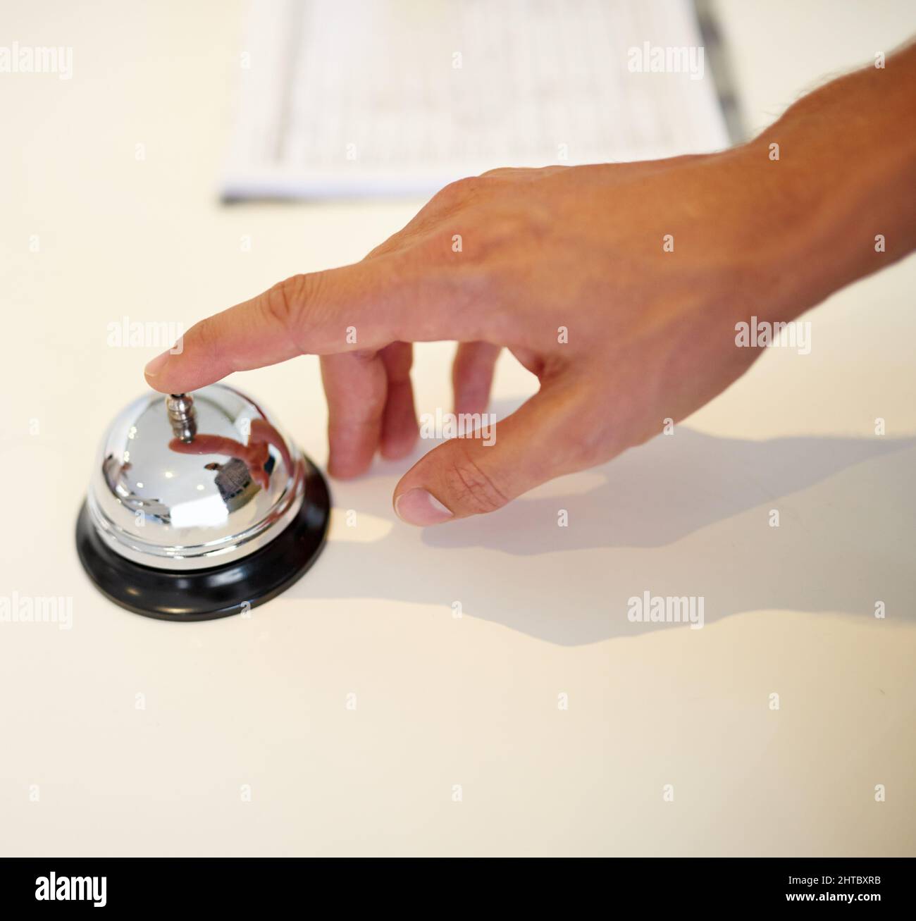 Ringing in his holiday. Shot of a hand ringing a bell at a hotel check ...