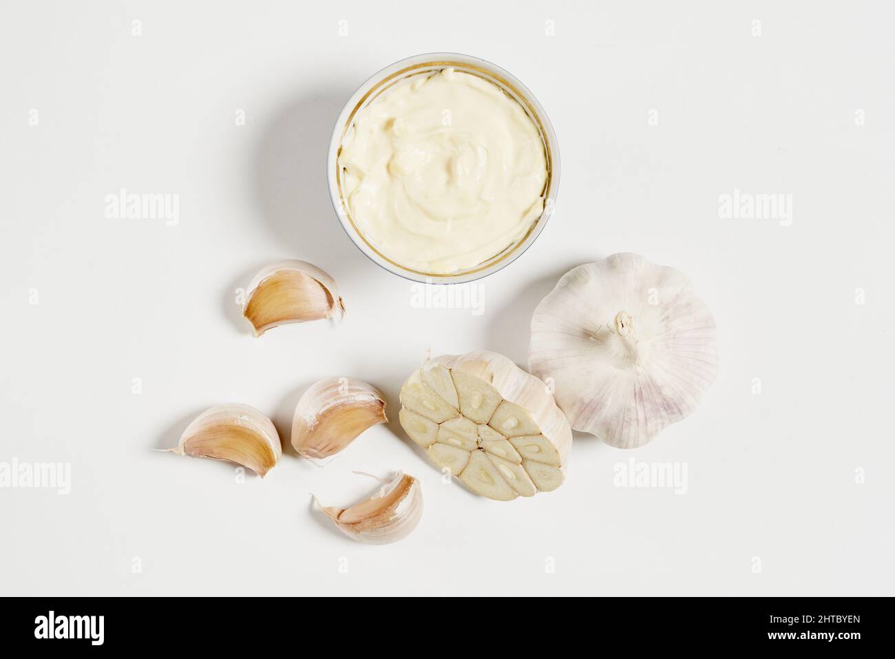 Fresh garlic slices and a bowl of garlic sauce isolated on white ...