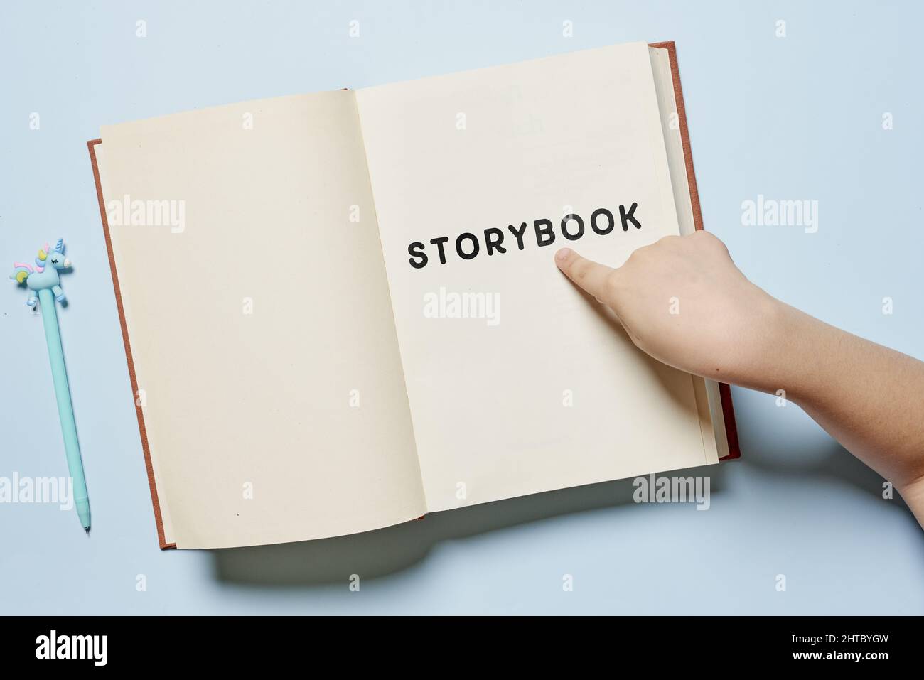 Top view of a child hand pointing a "storybook" word in the book on the ...