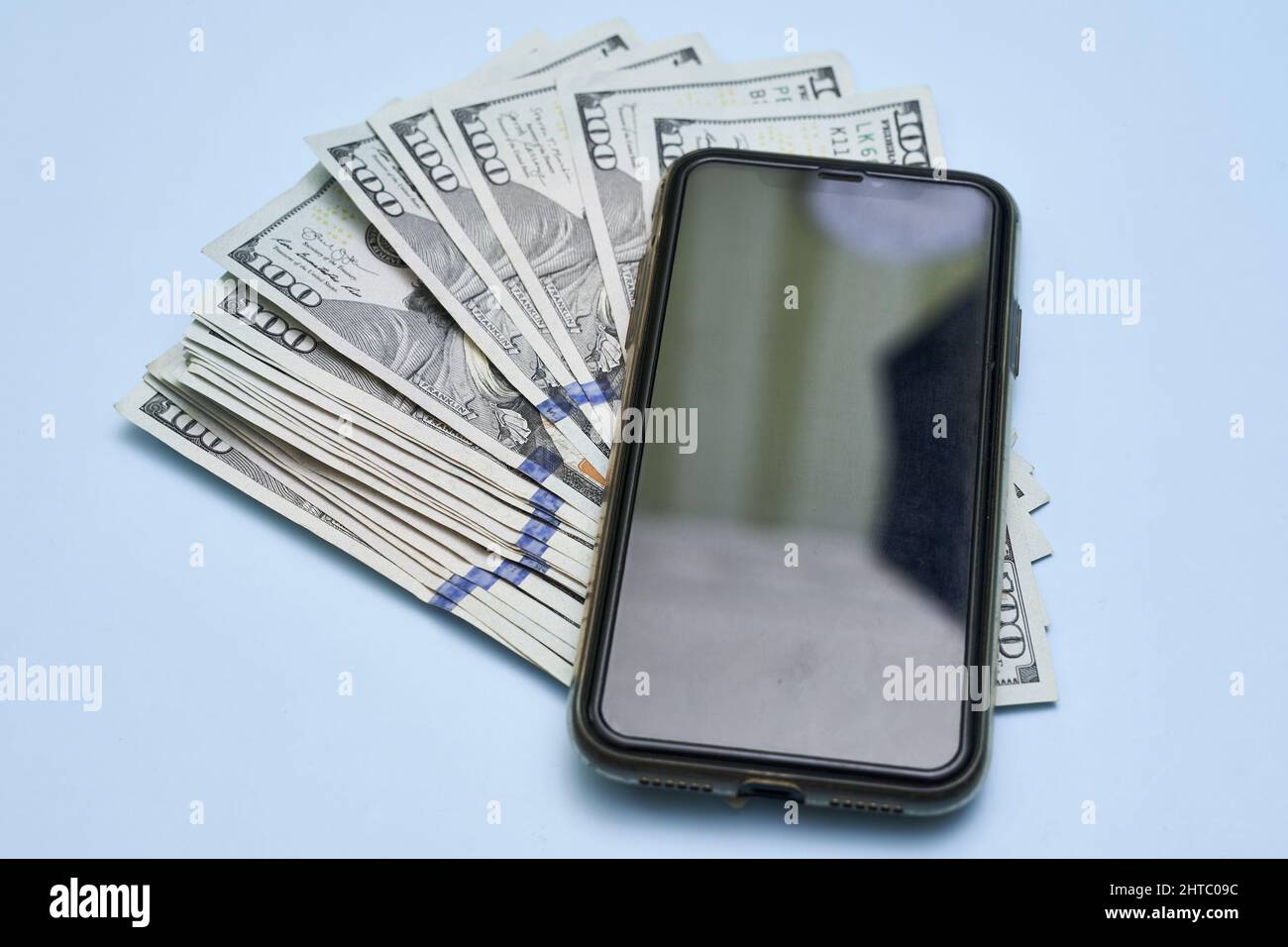 Closeup shot of a phone on a pile of money on a blue background Stock ...